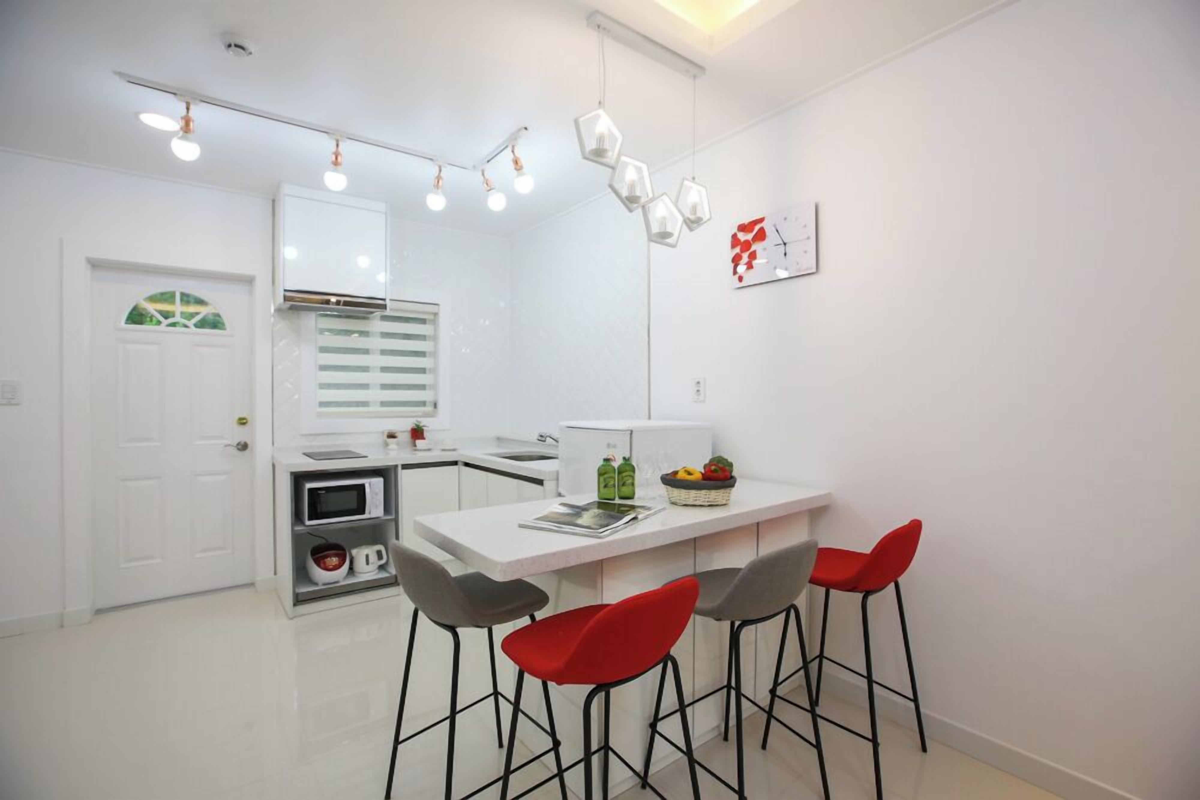 Uma cozinha moderna com armários brancos, uma ilha central com banquetas e uma área de refeições.