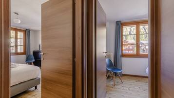 Quarto com cama, uma cadeira e vista para um edifício pela janela.
