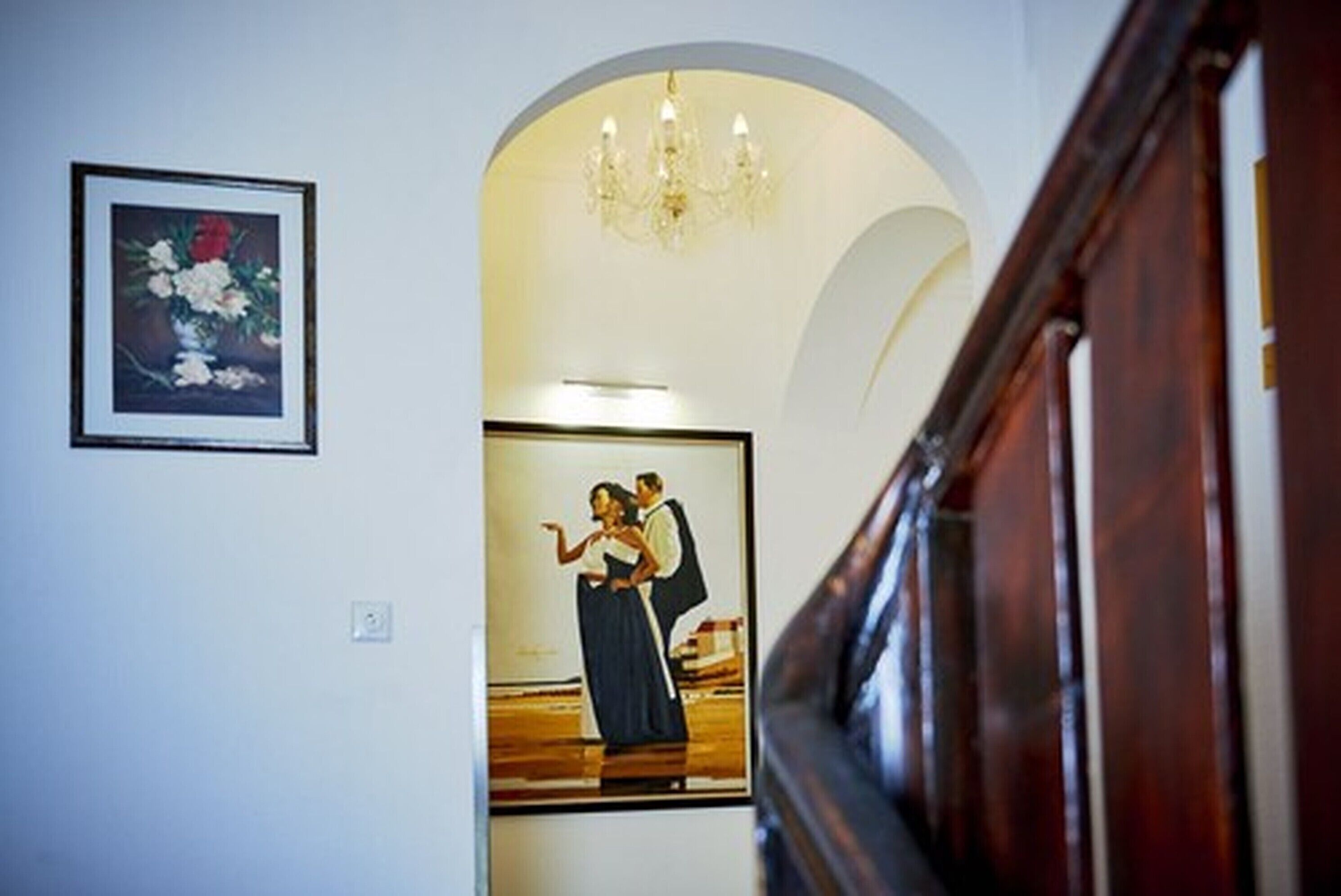 Uma escadaria com um candelabro e quadros nas paredes.