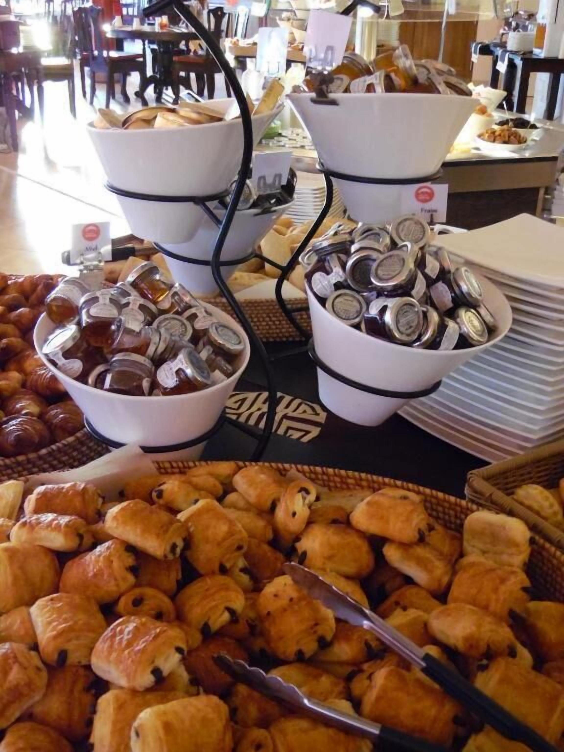 Buffet com diversos itens de comida, incluindo doces, geleias e acompanhamentos.