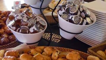 Buffet com diversos itens de comida, incluindo doces, geleias e acompanhamentos.