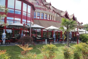 Restaurante ao ar livre com guarda-sóis vermelhos e brancos, mesas e cadeiras.