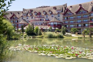 Um hotel com várias varandas, um pátio central com um lago e flores de lótus, e um estilo arquitetônico tradicional.