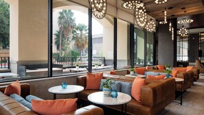 Uma área de lounge moderna com sofás de couro, mesas redondas e luminárias pendentes.