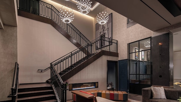 Uma sala de estar ampla com escada, lareira e luminárias modernas.