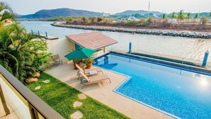 Uma piscina com vista para um rio e colinas ao fundo.