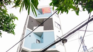 Um edifício moderno com fachada azul e branca, entrada com portão e fios elétricos aparentes.