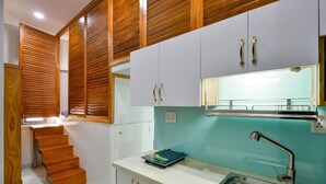 Uma cozinha moderna com armários brancos, painel de fundo azul-esverdeado e uma pia de aço inoxidável.