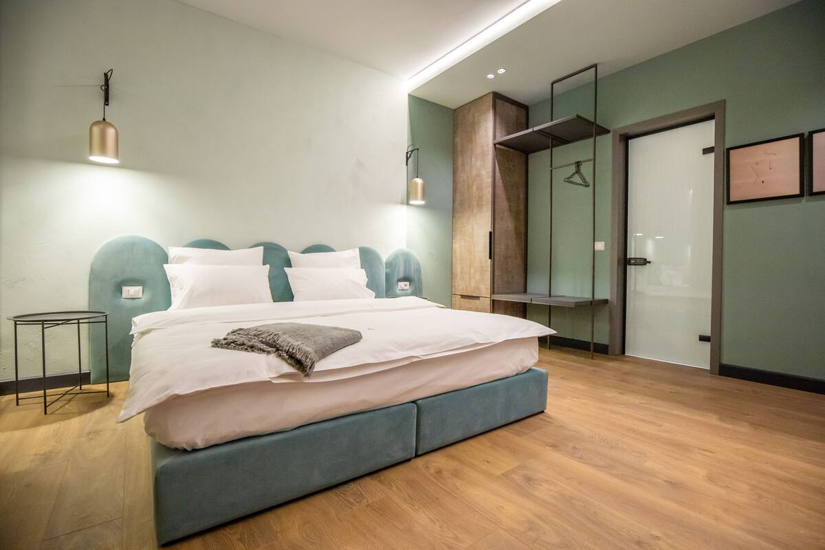 Um quarto moderno com uma cama grande, um guarda-roupa de madeira e uma pequena mesa de cabeceira.