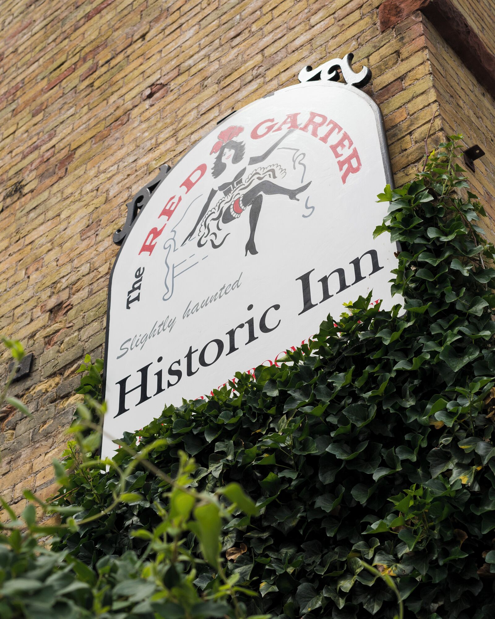 Placa do The Red Rooster Historic Inn, parcialmente coberta por hera.