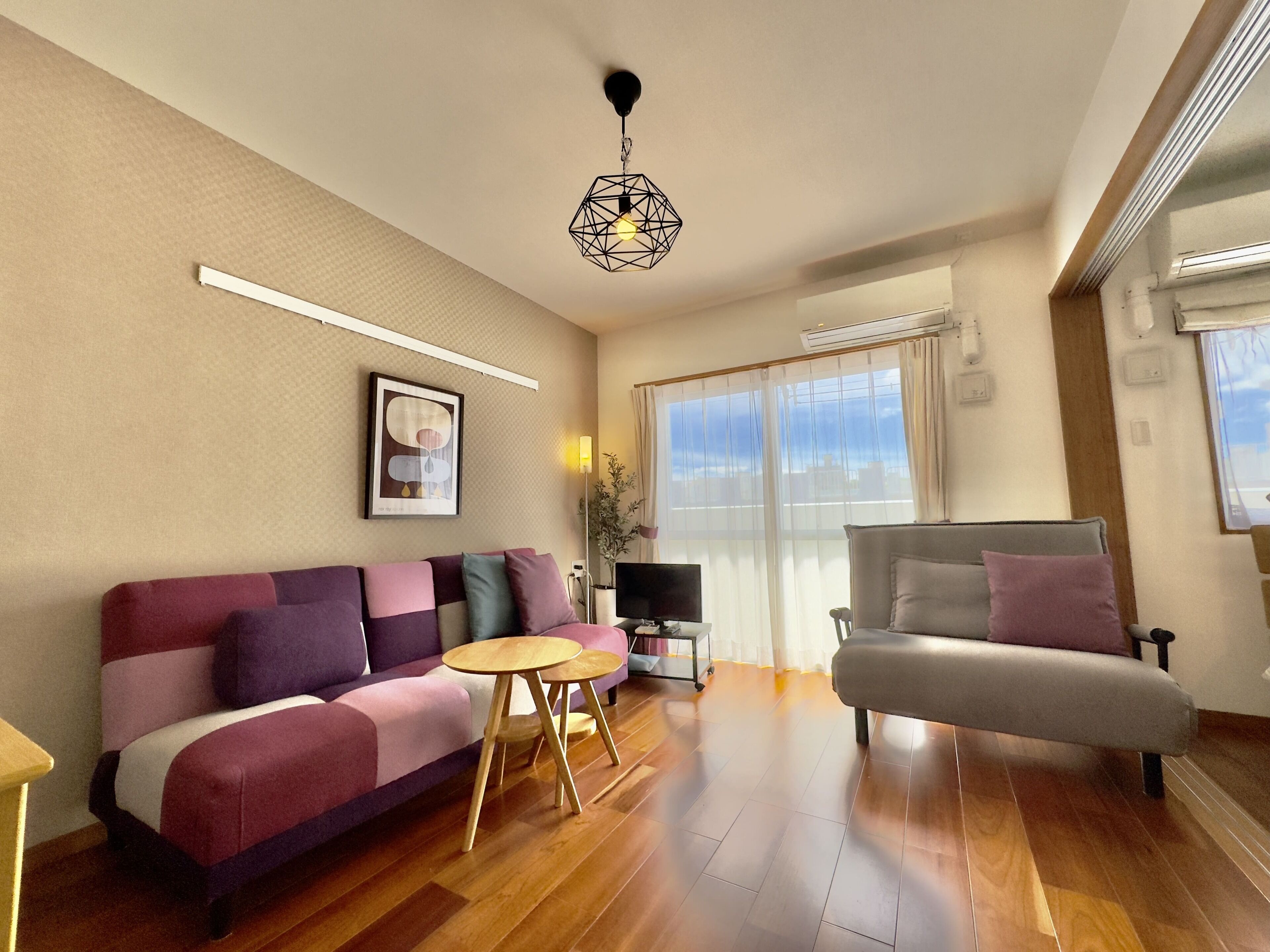Uma sala de estar moderna com um sofá, uma poltrona, uma mesinha e uma televisão.