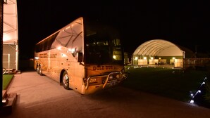 Um ônibus estacionado à noite próximo a um edifício com estrutura em cúpula.