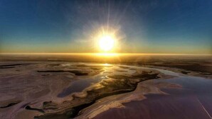 Ampla paisagem com uma grande massa de água refletindo o sol.