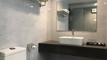 Uma casa de banho moderna com sanita branca, lavatório com bancada escura e espelho sobre o lavatório.