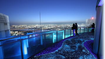 Vista noturna de um ponto alto com vista para um horizonte urbano com edifícios iluminados.