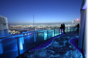 Vista noturna de um ponto alto com vista para um horizonte urbano com edifícios iluminados.