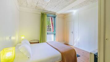 Quarto com cama, janela com cortinas, porta e luminária no teto.