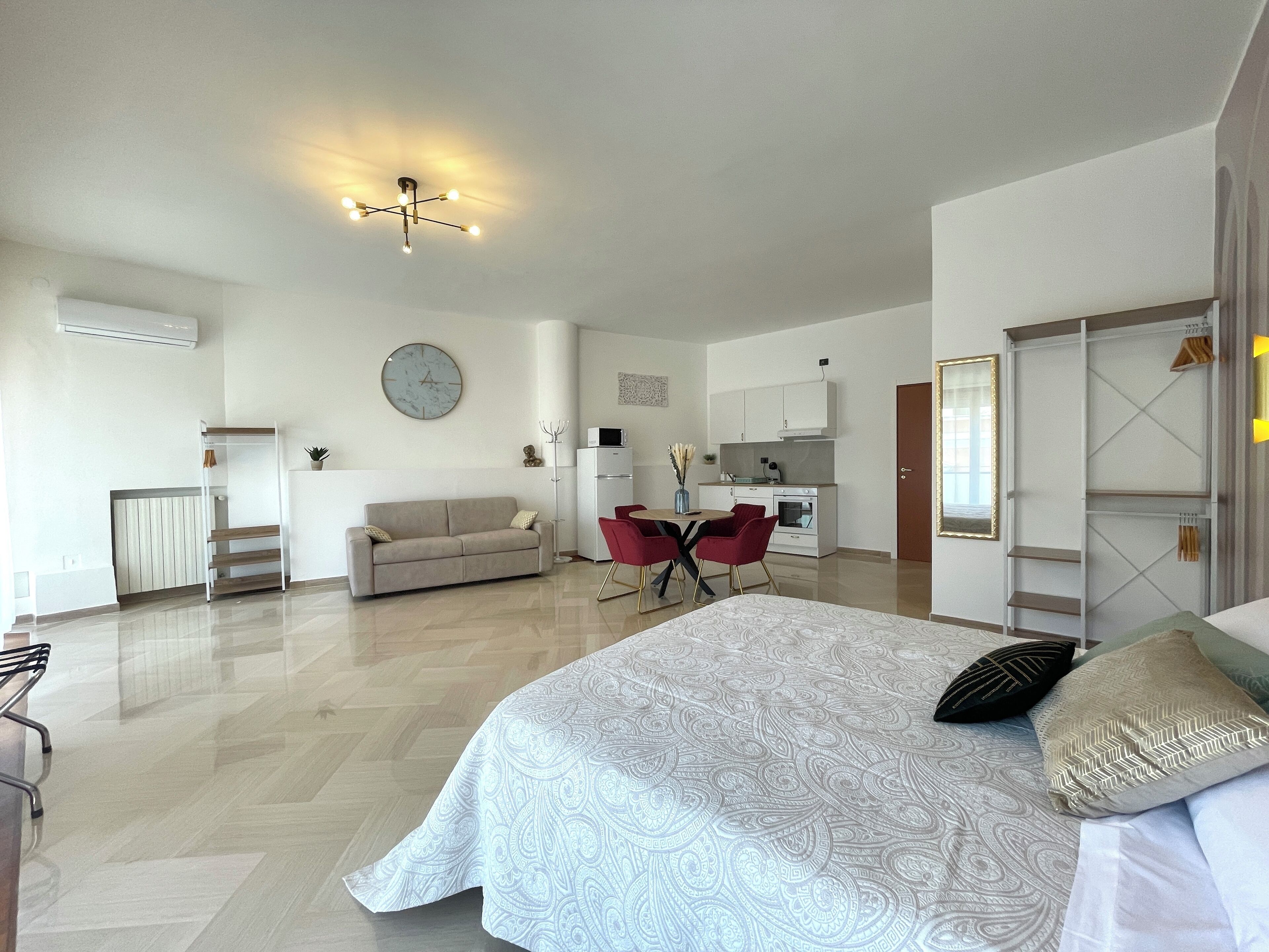 Quarto moderno com cama grande, área de refeições, cozinha e sala de estar.