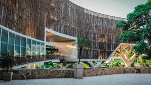 Um edifício moderno com fachada curva, grandes janelas e base de pedra.
