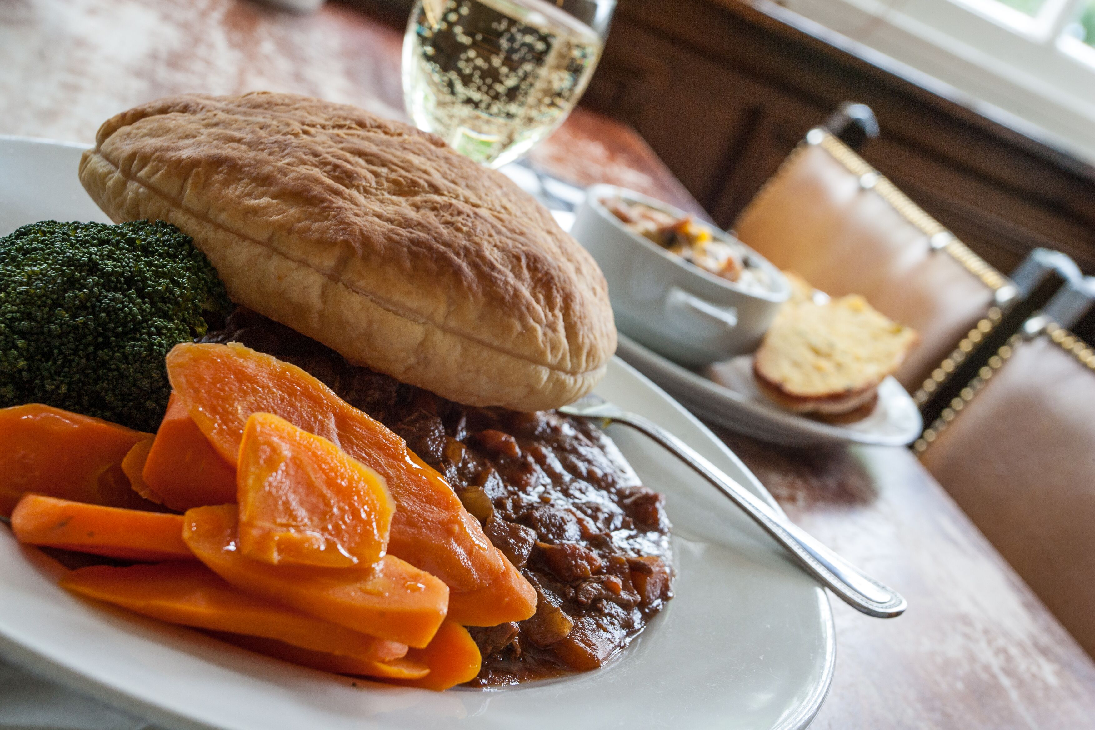Um prato com sanduíche de carne, cenouras e brócolis.