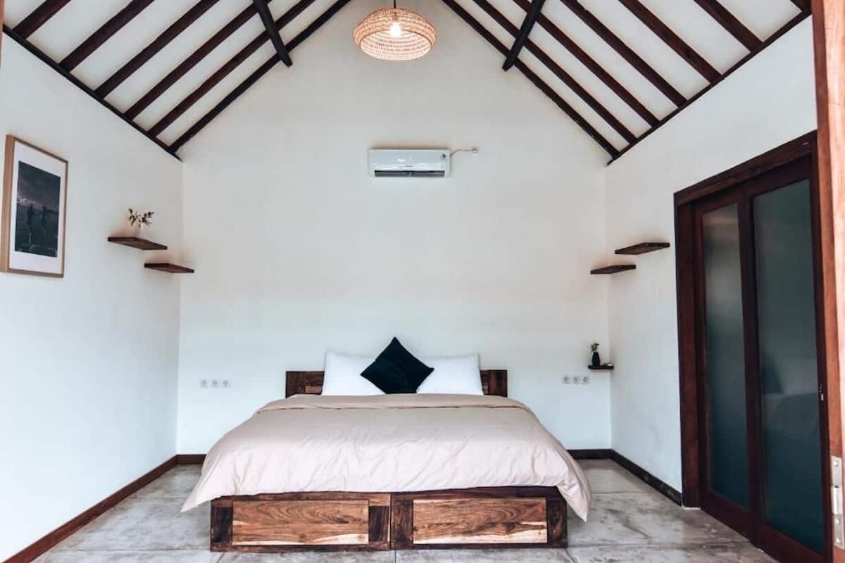 Quarto com cama, cabeceira de madeira, ventilador de teto e janela.