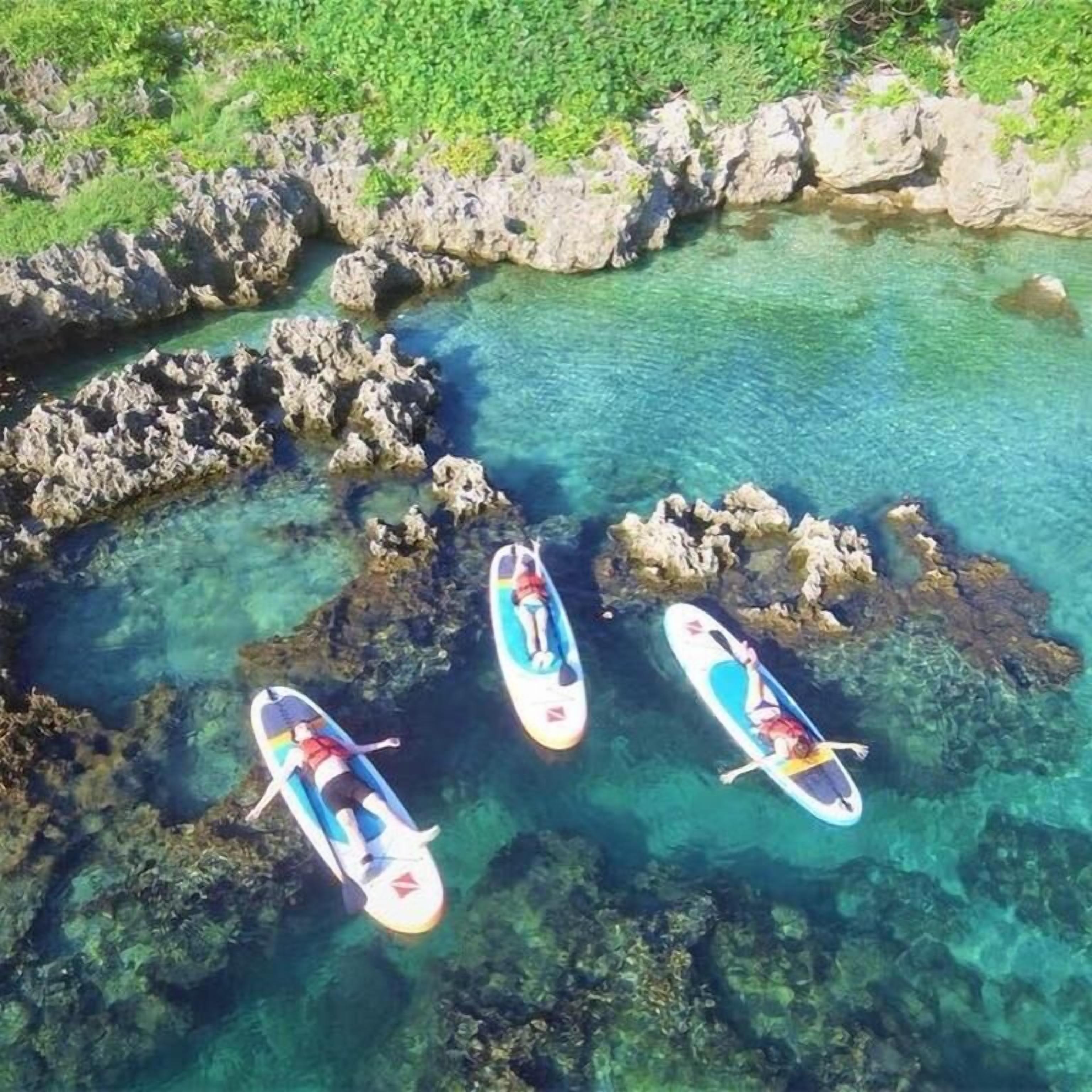 Três caiaques em águas claras perto de margens rochosas.