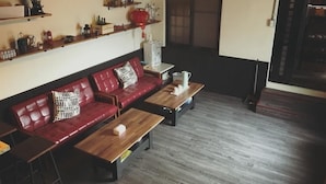 Uma sala de estar aconchegante com um sofá de couro vermelho, mesa de centro de madeira e estantes com diversos objetos.
