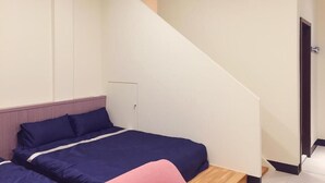 Um quarto com uma cama, um banco de madeira, uma porta branca e uma escada.