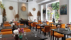 Um restaurante com mesas, cadeiras, decoração na parede e uma estátua de Buda.