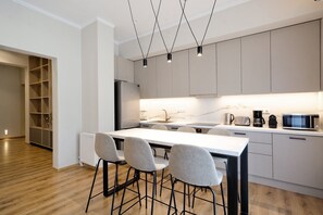Cozinha moderna com ilha central, banquetas e eletrodomésticos embutidos.