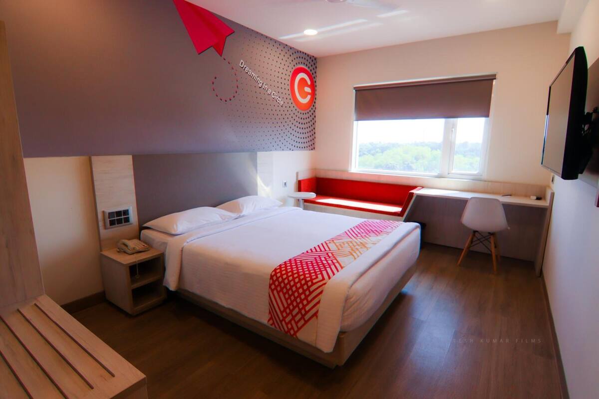 Quarto de hotel moderno com uma cama grande, uma escrivaninha e uma janela.