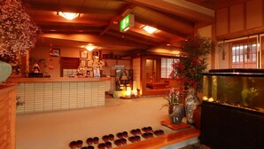 Decoração tradicional japonesa com uma mesa de recepção, um aquário e uma fileira de sapatos.