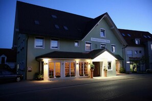 Um hotel com arquitetura europeia tradicional, apresentando uma entrada destacada com portas de vidro e uma placa acima da porta.