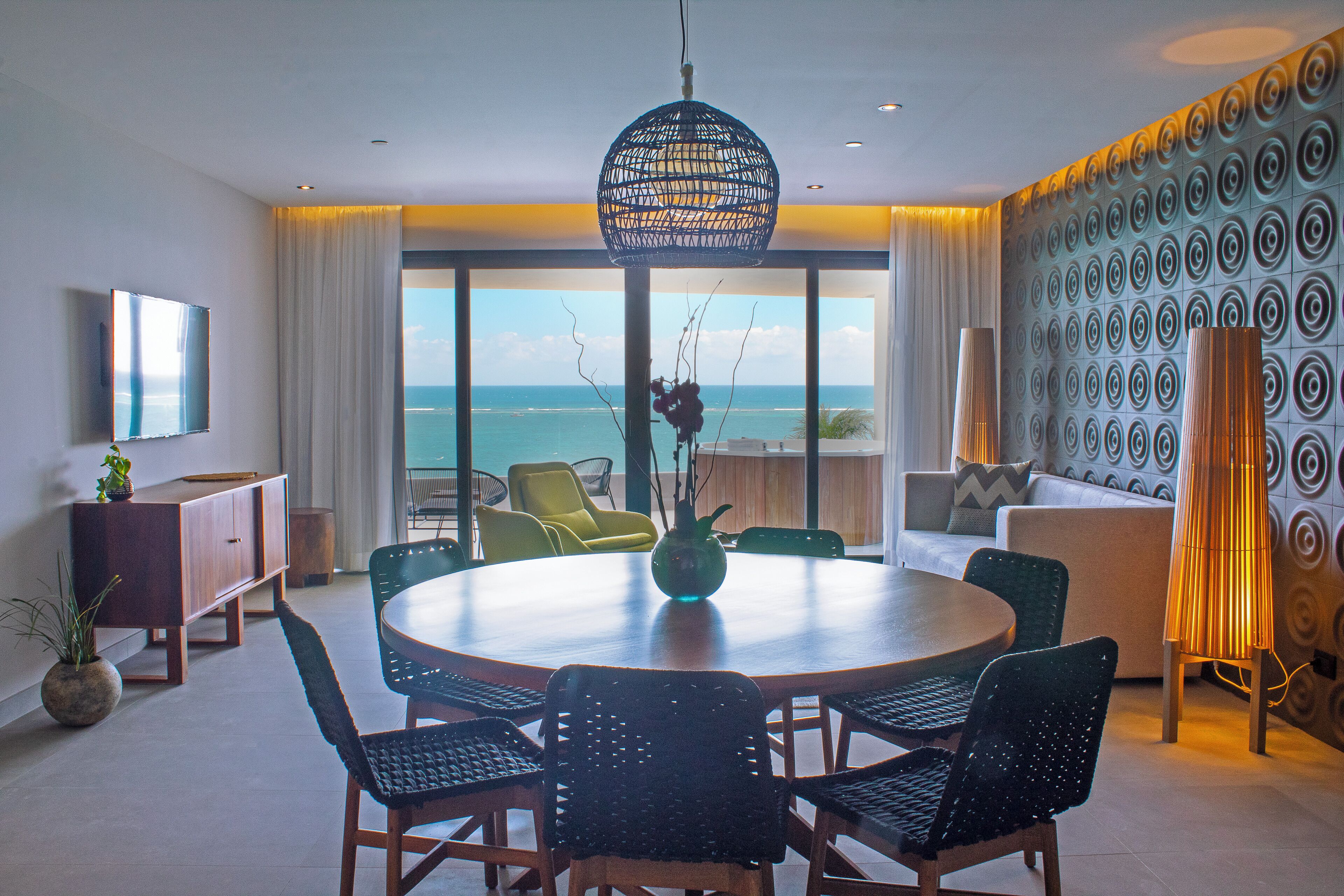 Uma sala de jantar moderna com uma mesa redonda, cadeiras e um lustre decorativo.