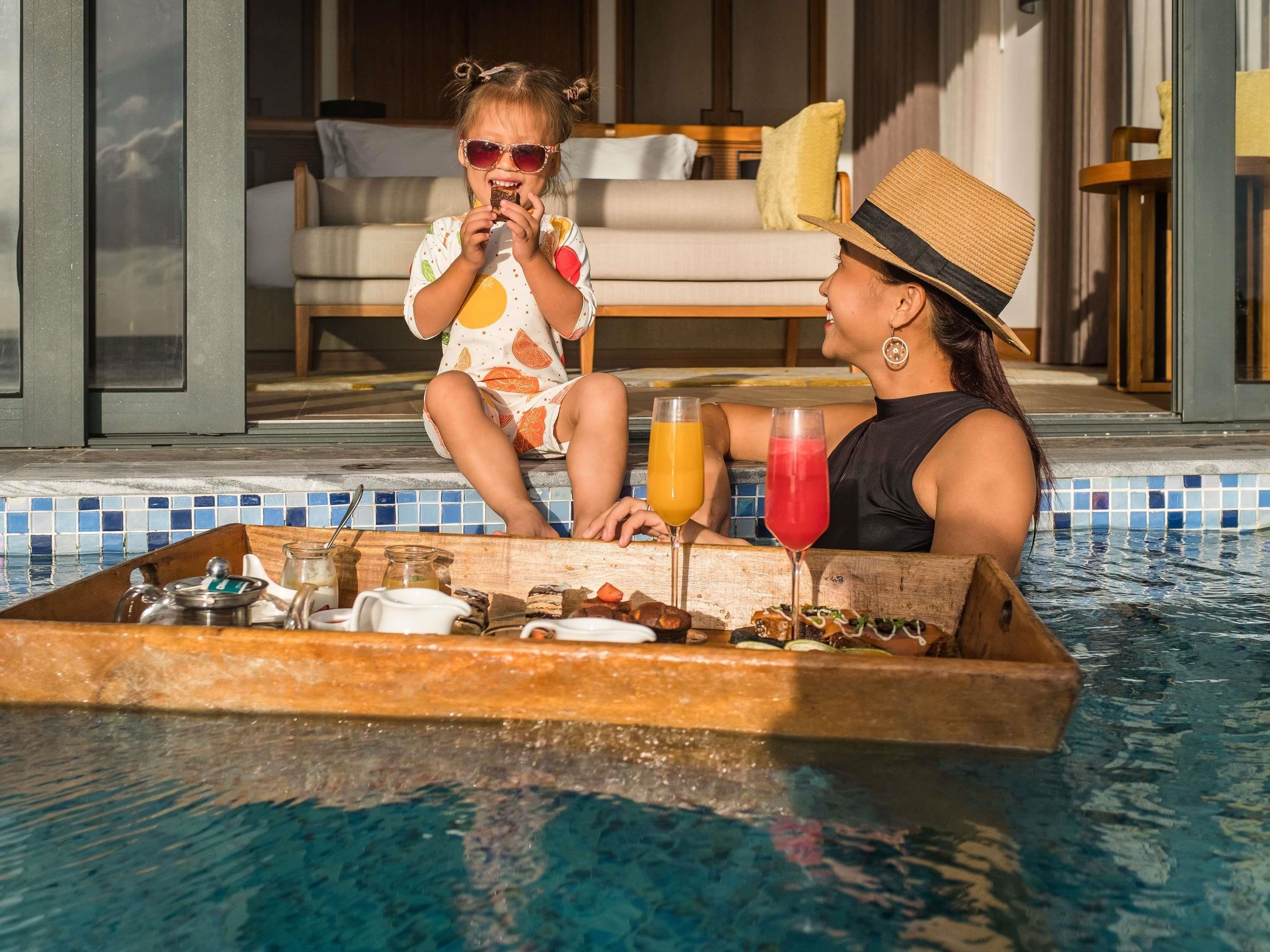 Ambiente à beira da piscina com uma mesa de jantar, duas pessoas e uma piscina.