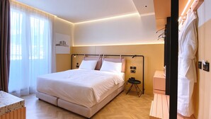 Quarto de hotel moderno com cama grande, mesas de cabeceira, escrivaninha e um porta-robes.