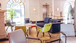 Um saguão moderno de hotel com área de estar, balcão de recepção e parede de mármore.