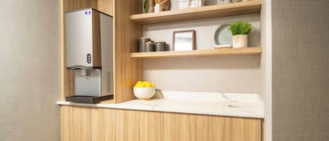 Uma cozinha compacta com geladeira embutida, pia e prateleiras de madeira com objetos decorativos.