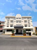 Um hotel com vários andares, entrada central e um céu claro.