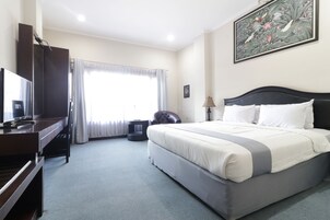 Quarto de hotel com cama, televisão, escrivaninha e cadeira.