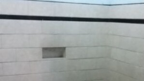 Um banheiro pequeno revestido com azulejos, com um vaso sanitário, uma pia e uma lixeira verde.