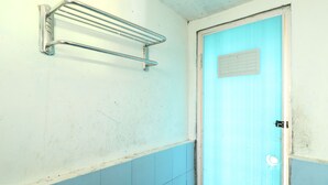 Um banheiro com porta azul, suporte de toalhas de metal e paredes azulejadas em azul.