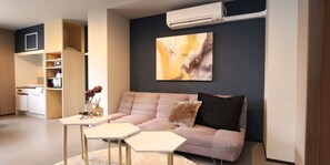 Uma sala de estar moderna com um sofá, duas mesas laterais, um vaso decorativo e um quadro na parede.