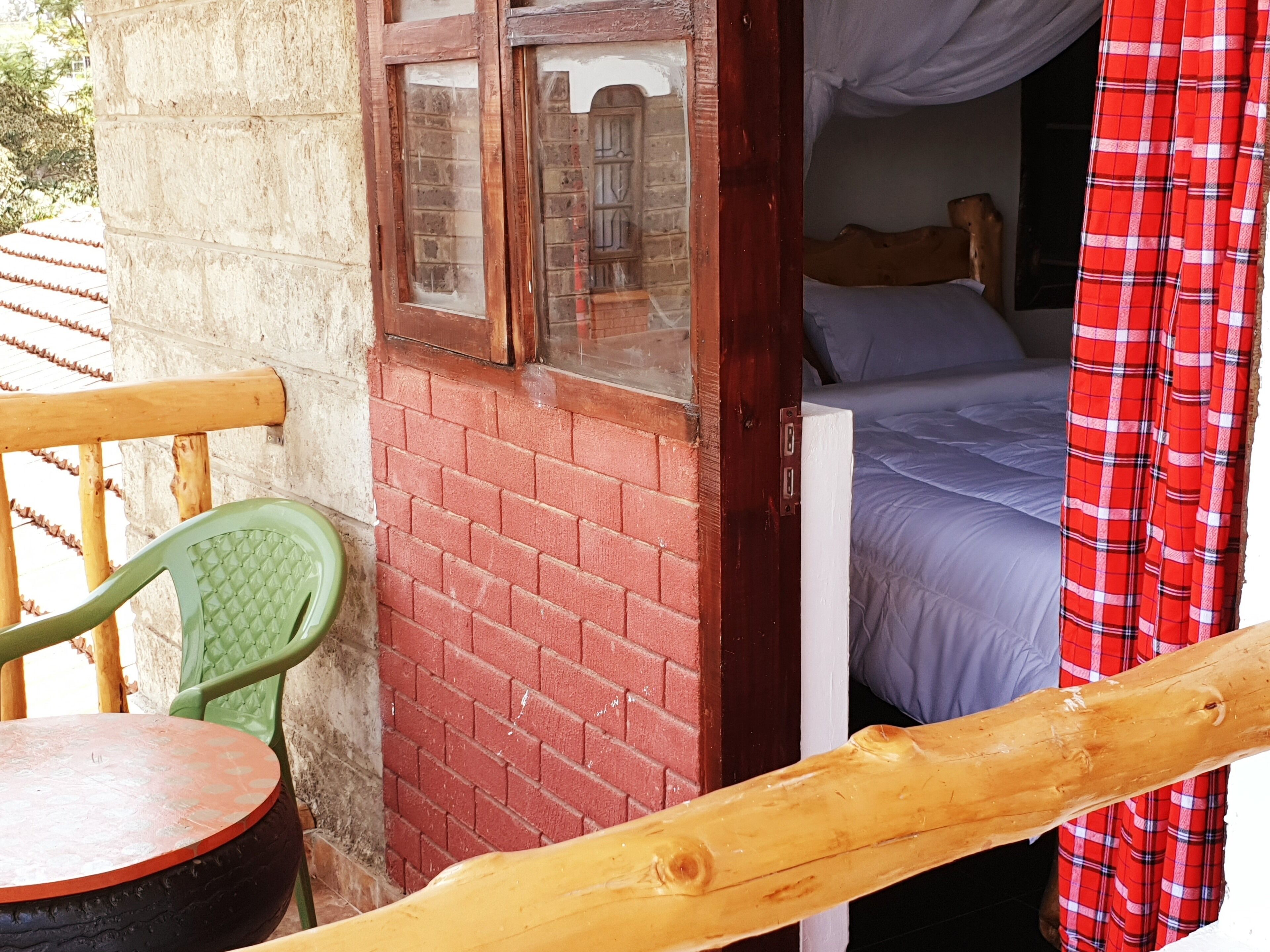 Um quarto com uma cama, janela, cadeira e mesa.