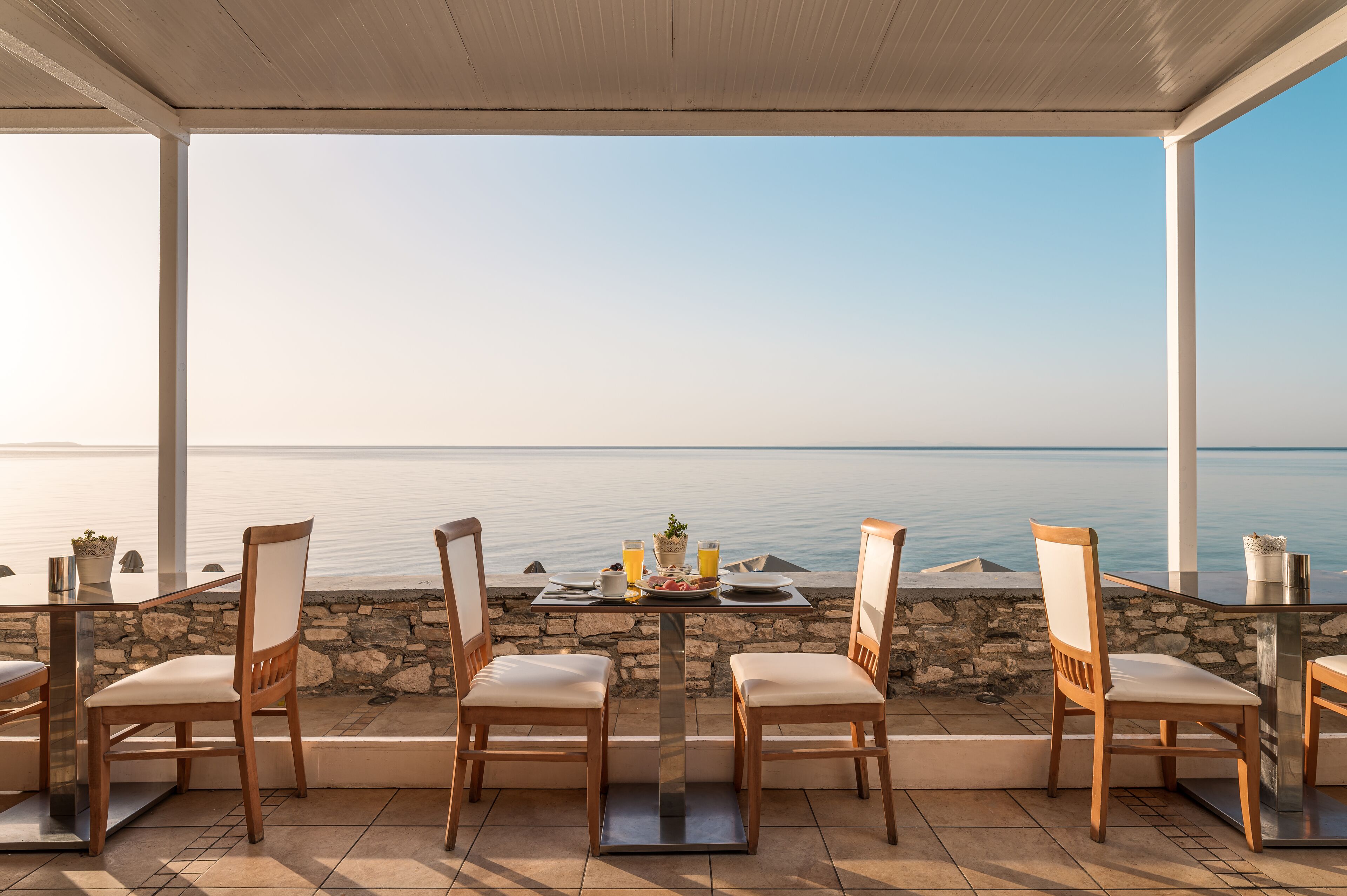 Terraço com mesa posta para o café da manhã, vista para o mar.