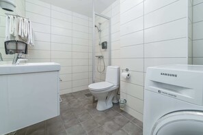 Casa de banho com lavatório branco, sanita e máquina de lavar roupa Samsung.