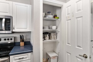 Cozinha com armários brancos, micro-ondas, fogão e bancada com porta-facas.