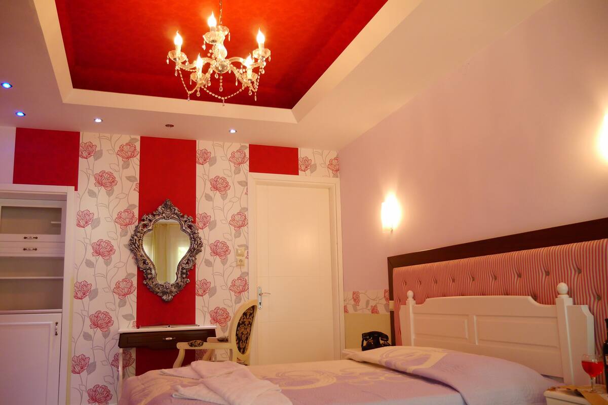 Quarto com cama, penteadeira, espelho e lustre.