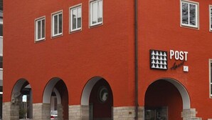 Um edifício vermelho com várias janelas e uma placa com a inscrição 'POST'.
