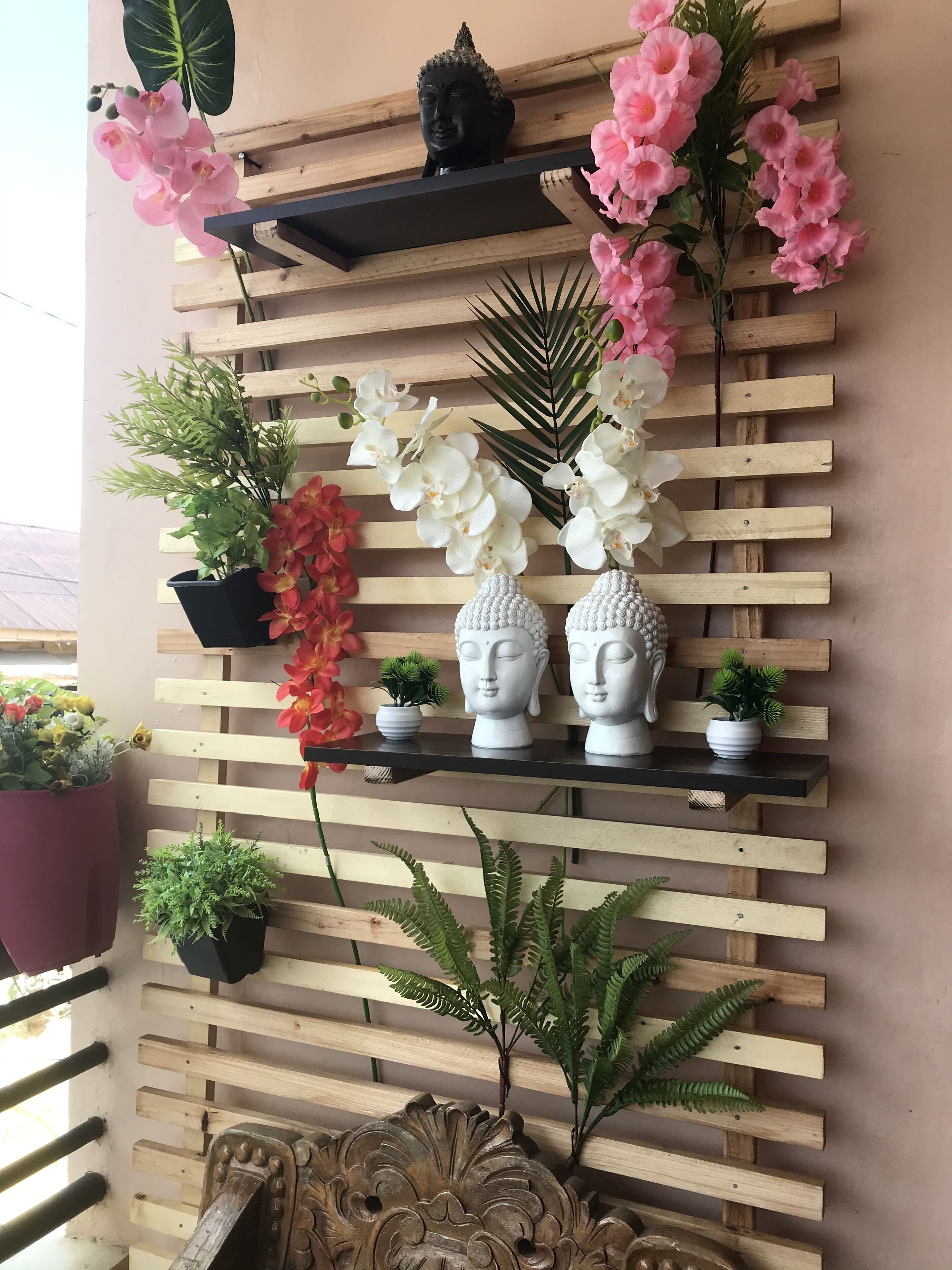 Estante de madeira fixada na parede com vários vasos de plantas e objetos decorativos.
